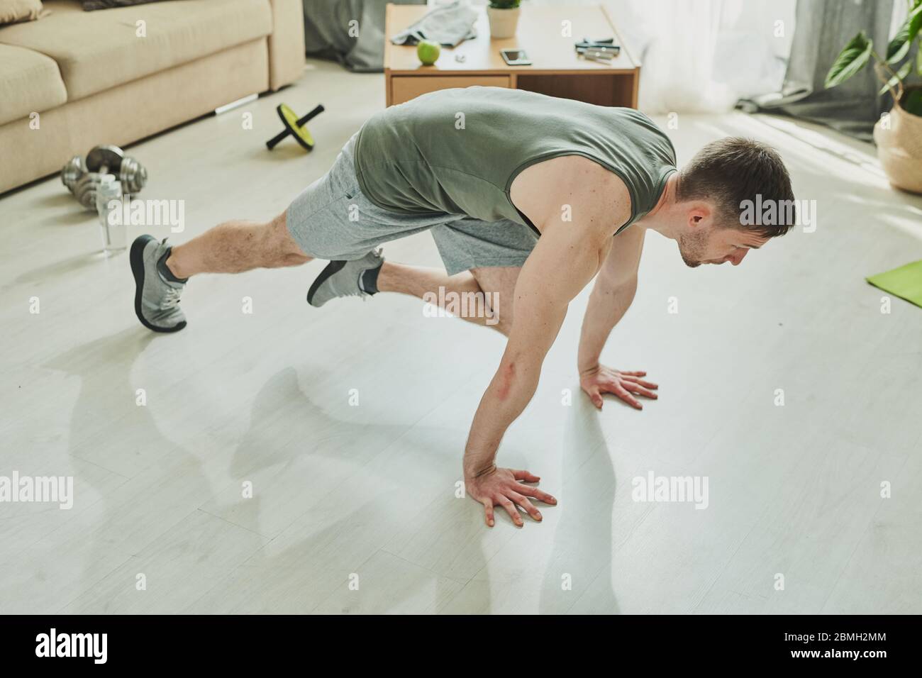 Young active man in sportswear standing on hands and one leg on the ...