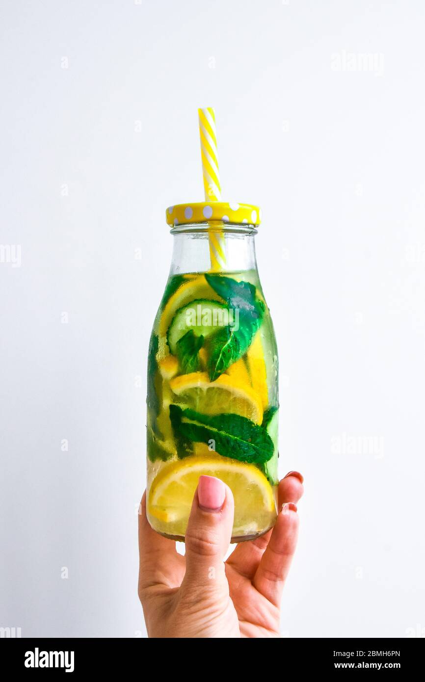 Female hand holdin Fresh cool lemon cucumber mint infused water detox drink, summer refreshing ...
