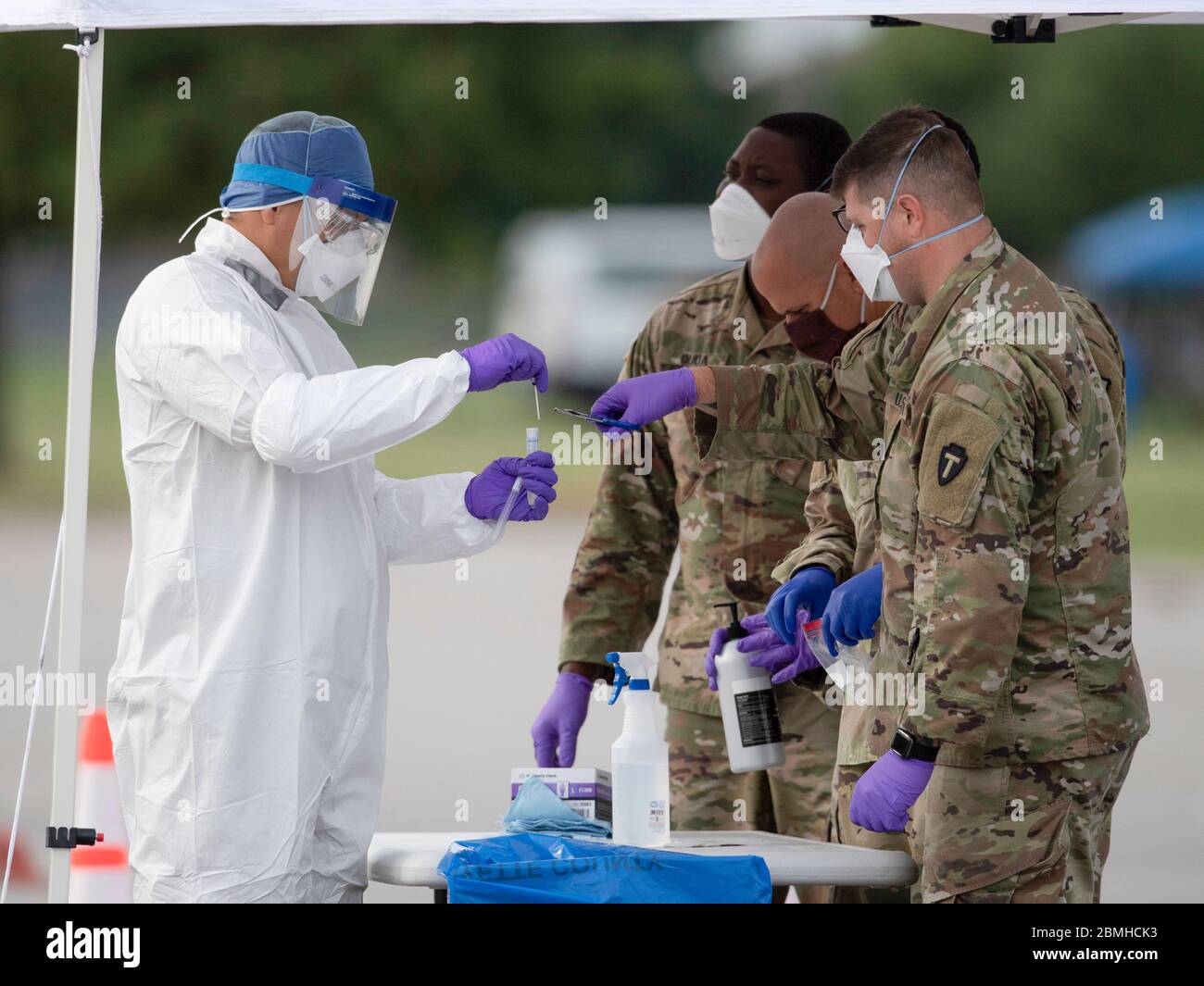 Spc. Nicholas Cisneros hands over a nasal swab taken from a patient as ...