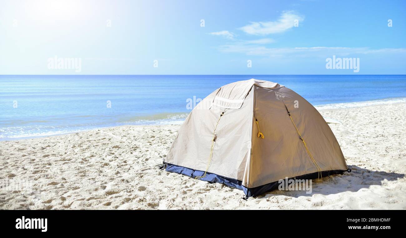 Sand-colored tourist tent on the seashore in the sand. Calm morning sea ...