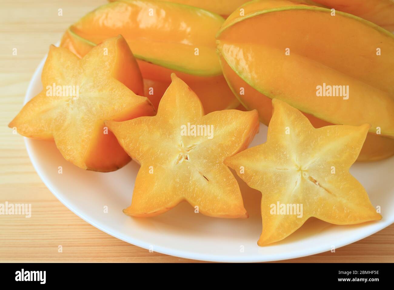 Closeup cross sections of juicy fresh ripe star fruits on a white plate ...