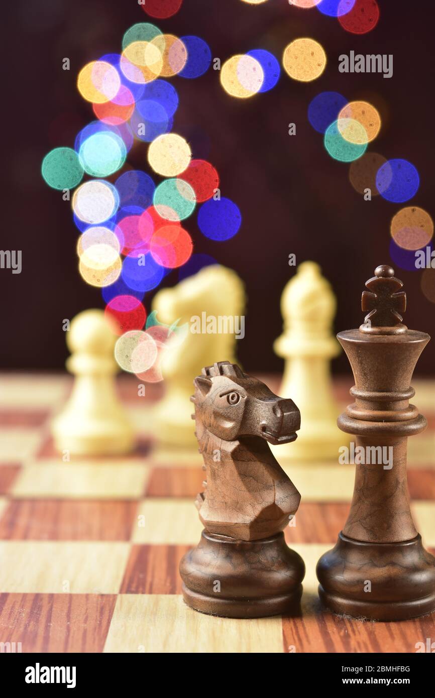 Chess pieces on the chessboard with colorful lights on the background ...