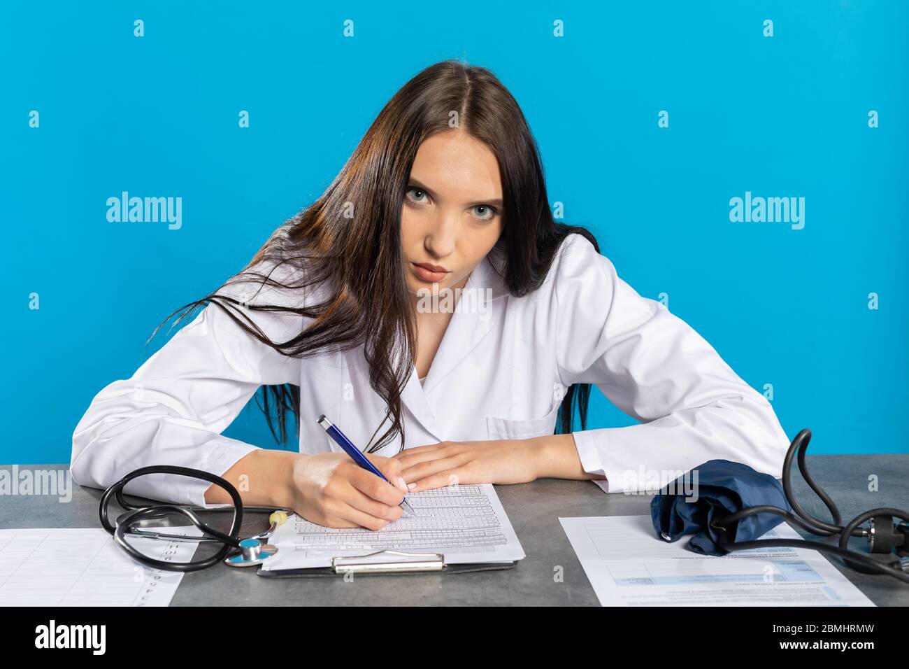 A young lady doctor writes the test results to the patient's card Stock ...