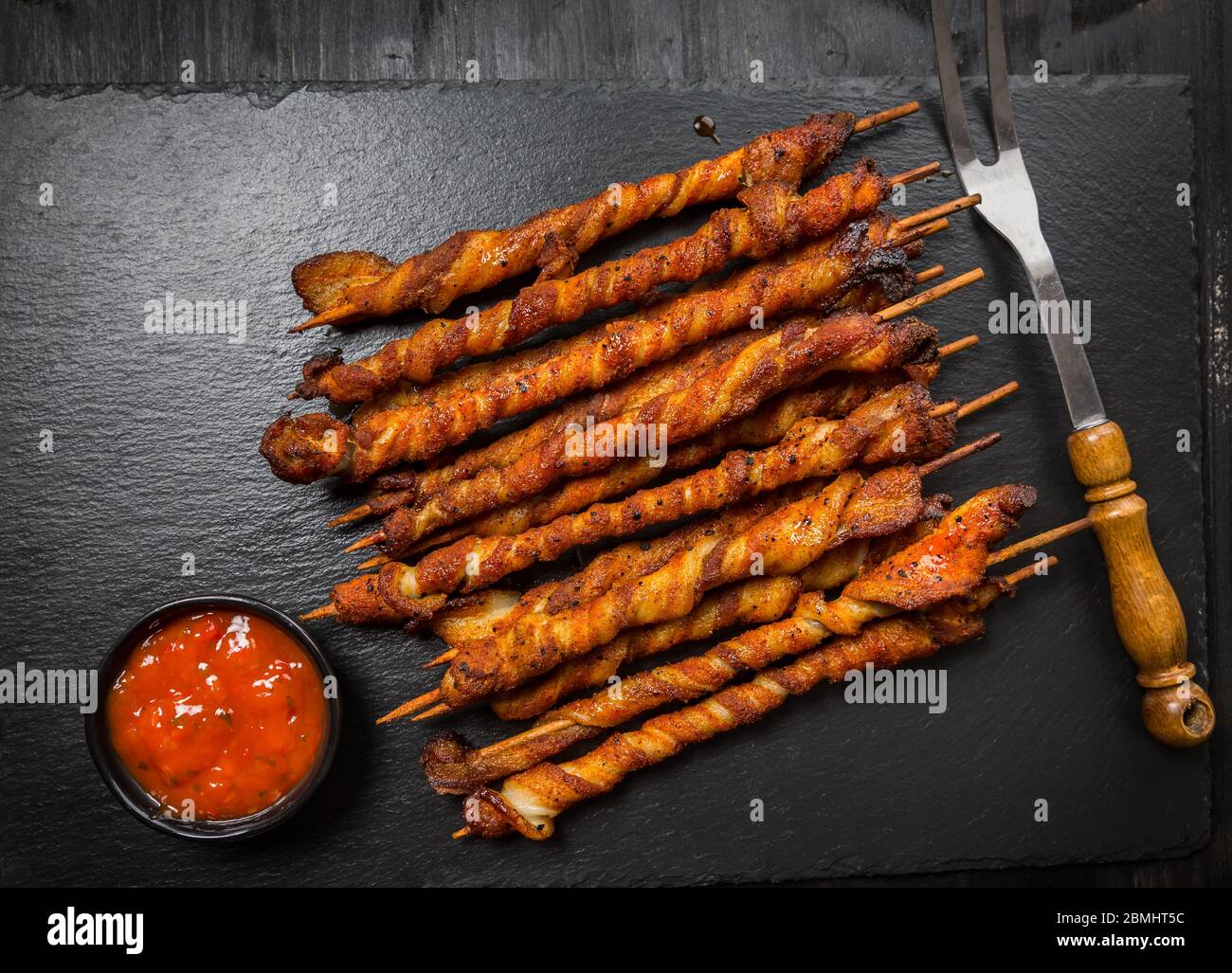 Grill skewer with hot salsa dip on black background Stock Photo - Alamy