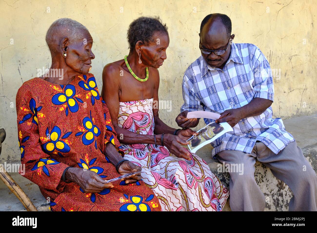Western dressed man showing old photographs to elderly Zulawa women ...