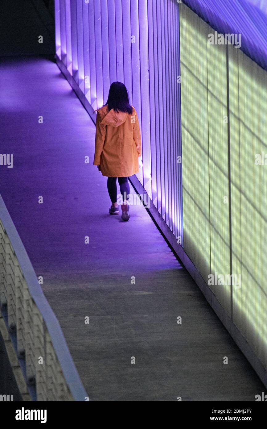 A woman walking alone through a pedestrian underpass in a city downtown ...