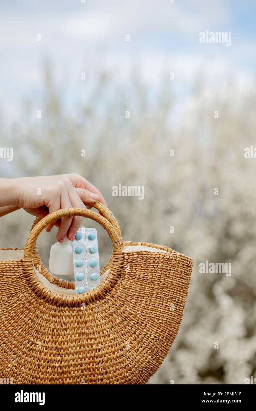 Woman's hand puts allergy pills in bag on blooming background Stock ...