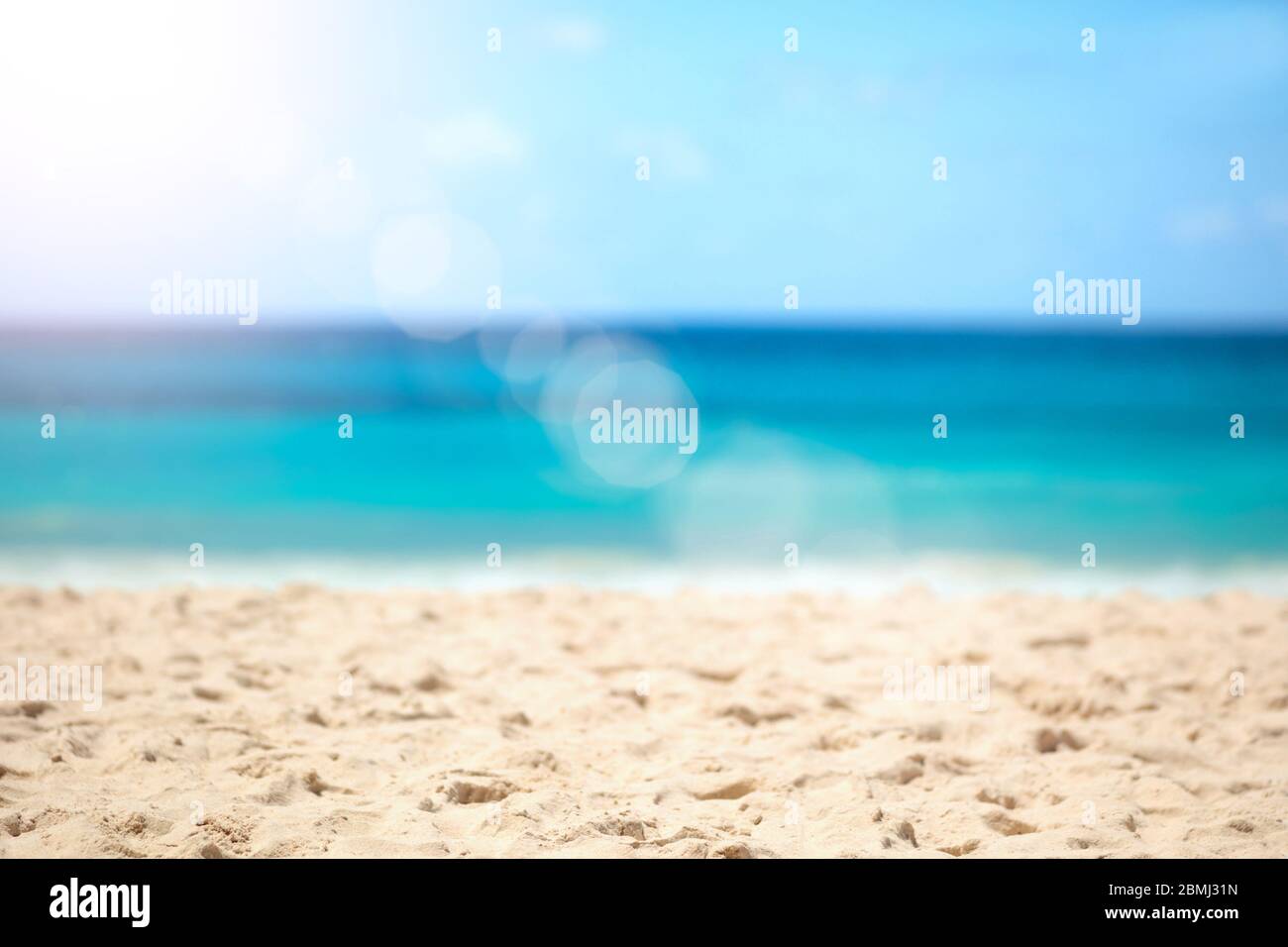 Blurred summer background, nature of tropical golden beach with rays of sun light. Golden sand ...