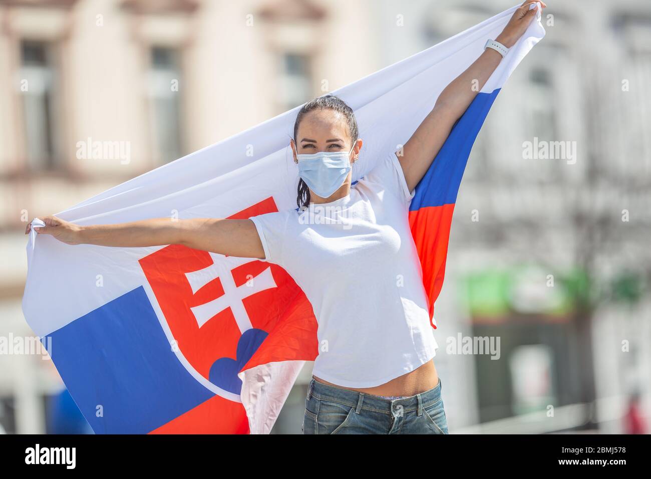 Slovak female fan holds a flag behind her on a street, wearing a face ...