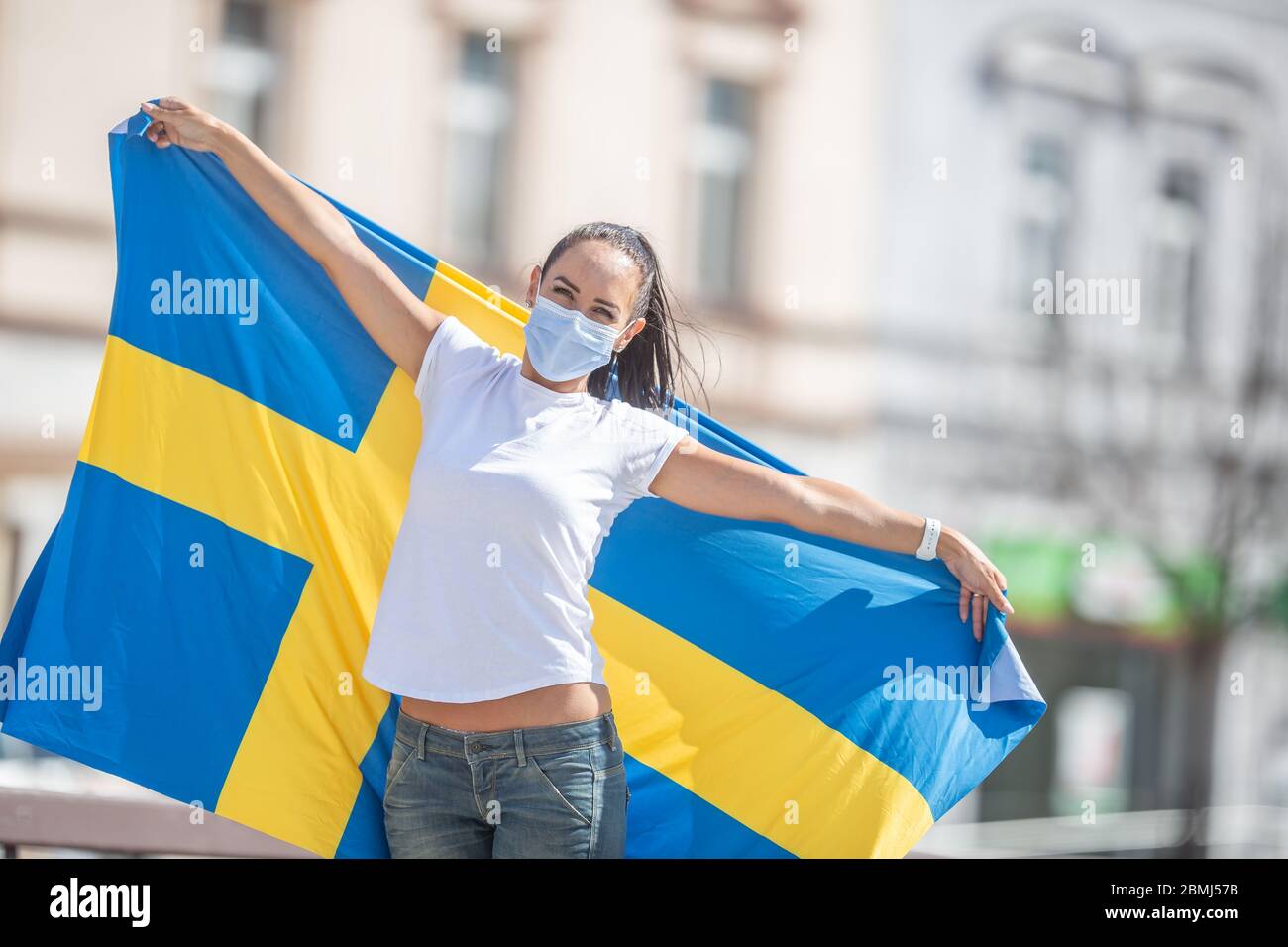 Beautiful smiling Swedish girl holds a flag while wearing a protective ...