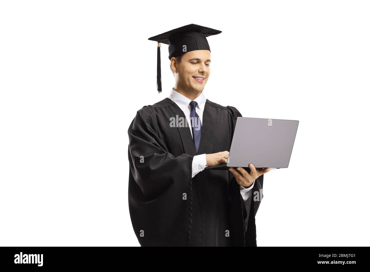Male graduate using a laptop computer isolated on white background ...