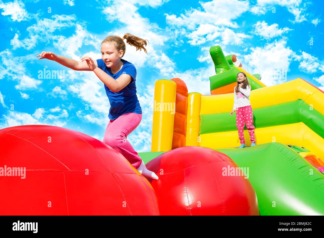 Happy little girls having lots of fun while jumping from ball to ball ...