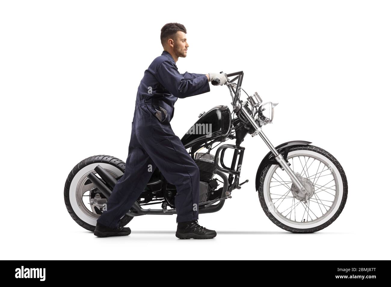 Full length profile shot of a motorcycle mechanic pushing a chopper ...