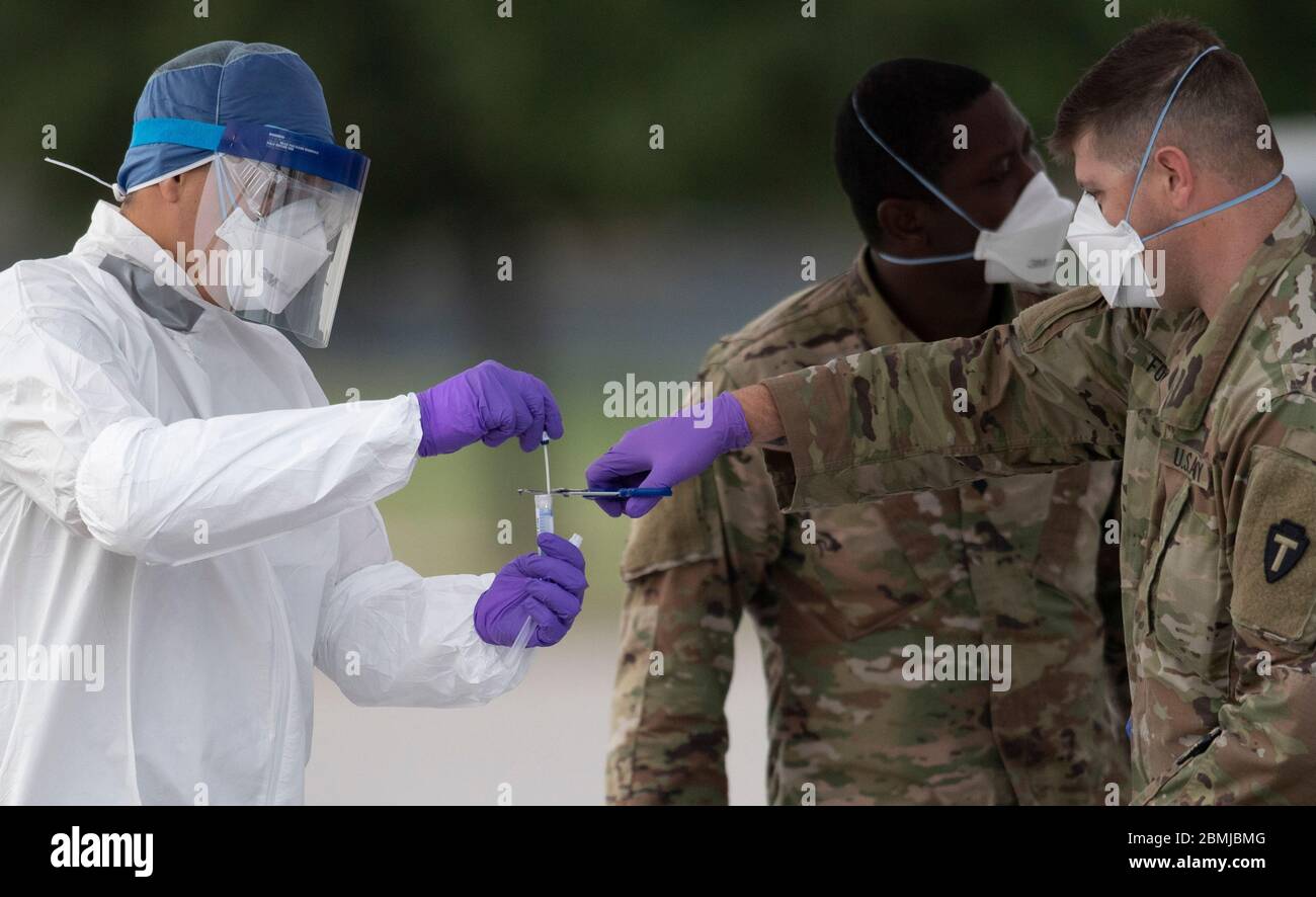 Spc. Nicholas Cisneros hands over a nasal swab taken from a patient as ...