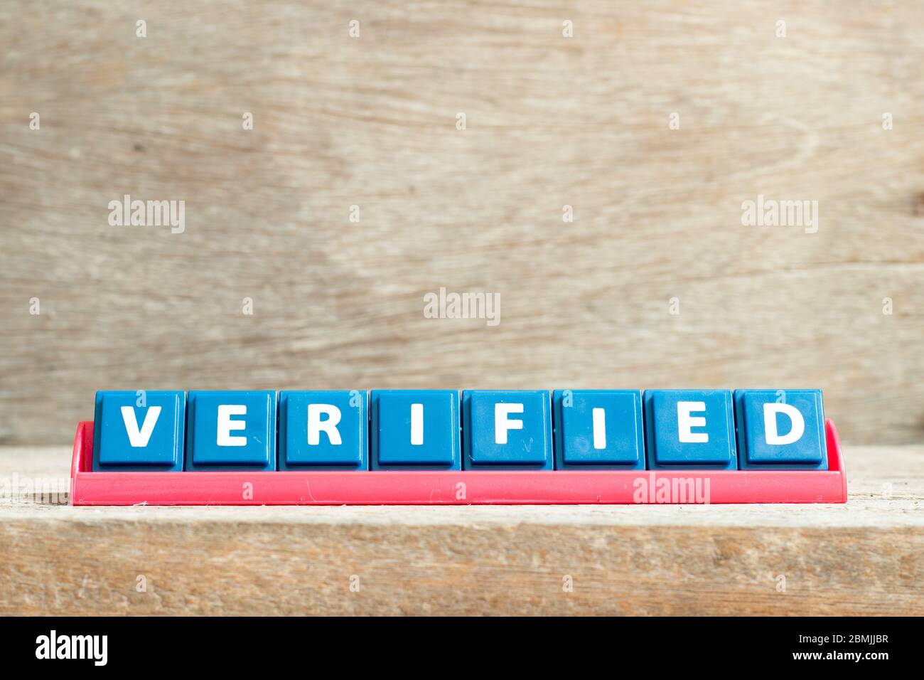 Tile letter on red rack in word verified on wood background Stock Photo ...