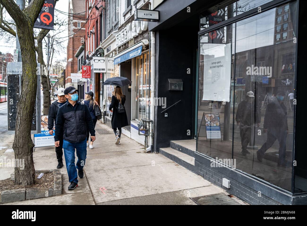 Locals wearing face masks on the streets of Downtown Toronto on a rainy ...