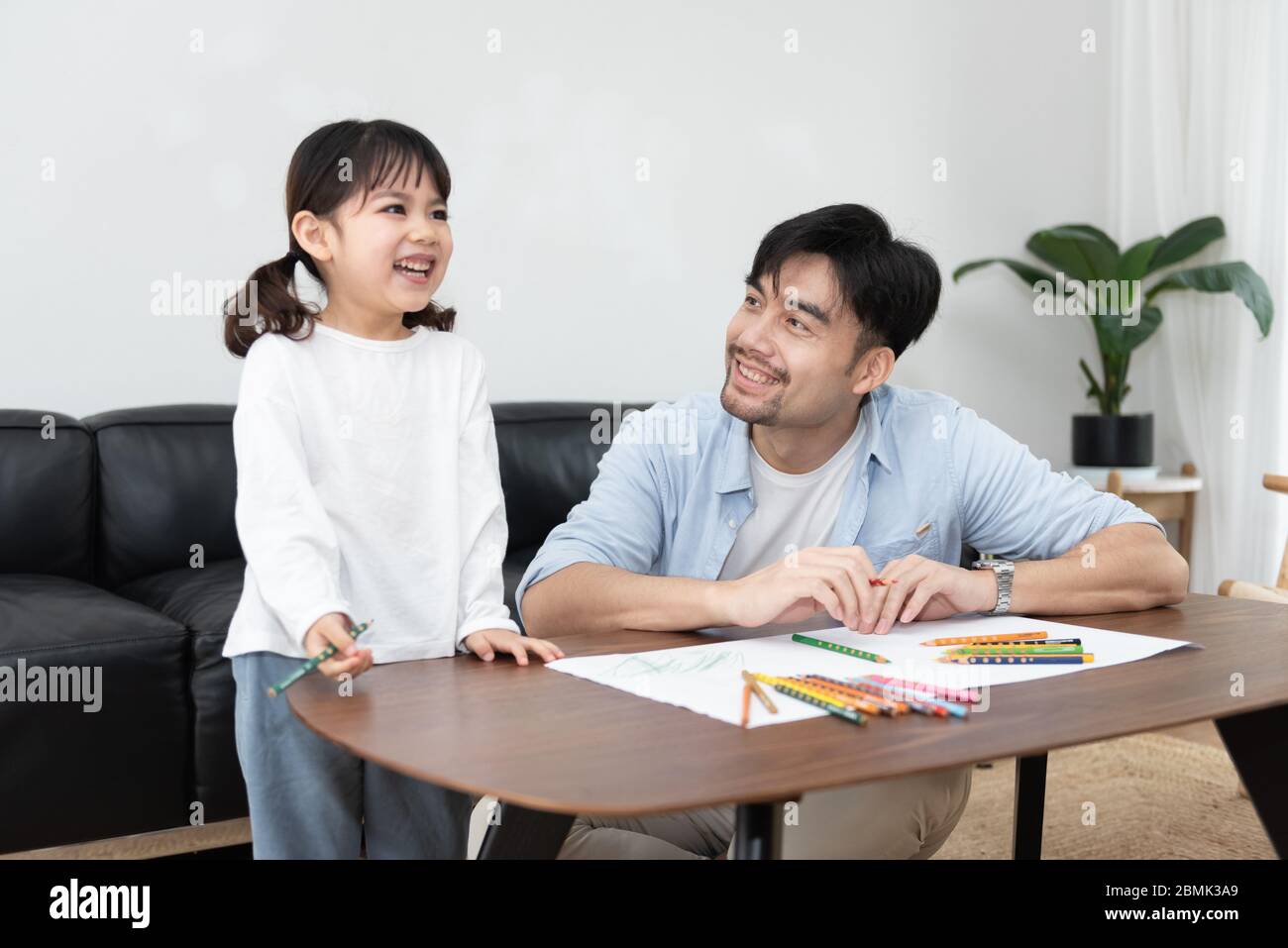 A pair of young Asian father and daughter are drawing in the living ...