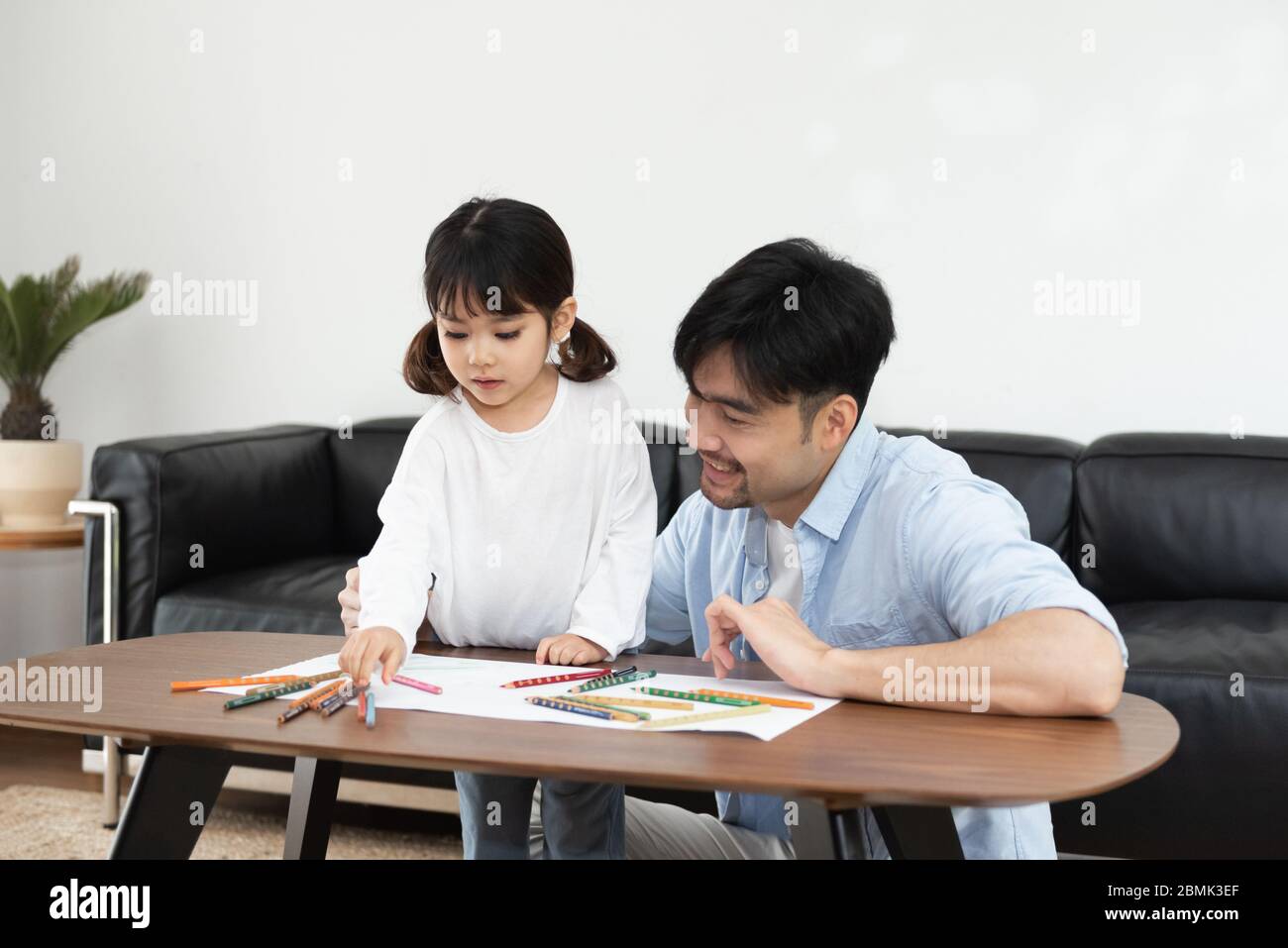 A pair of young Asian father and daughter are drawing in the living ...