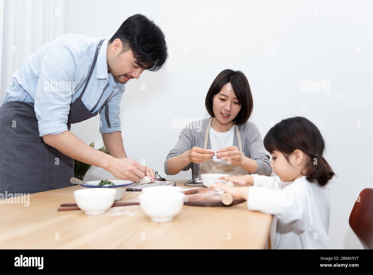 Young Asian mom and dad making dumplings with daughter Stock Photo - Alamy