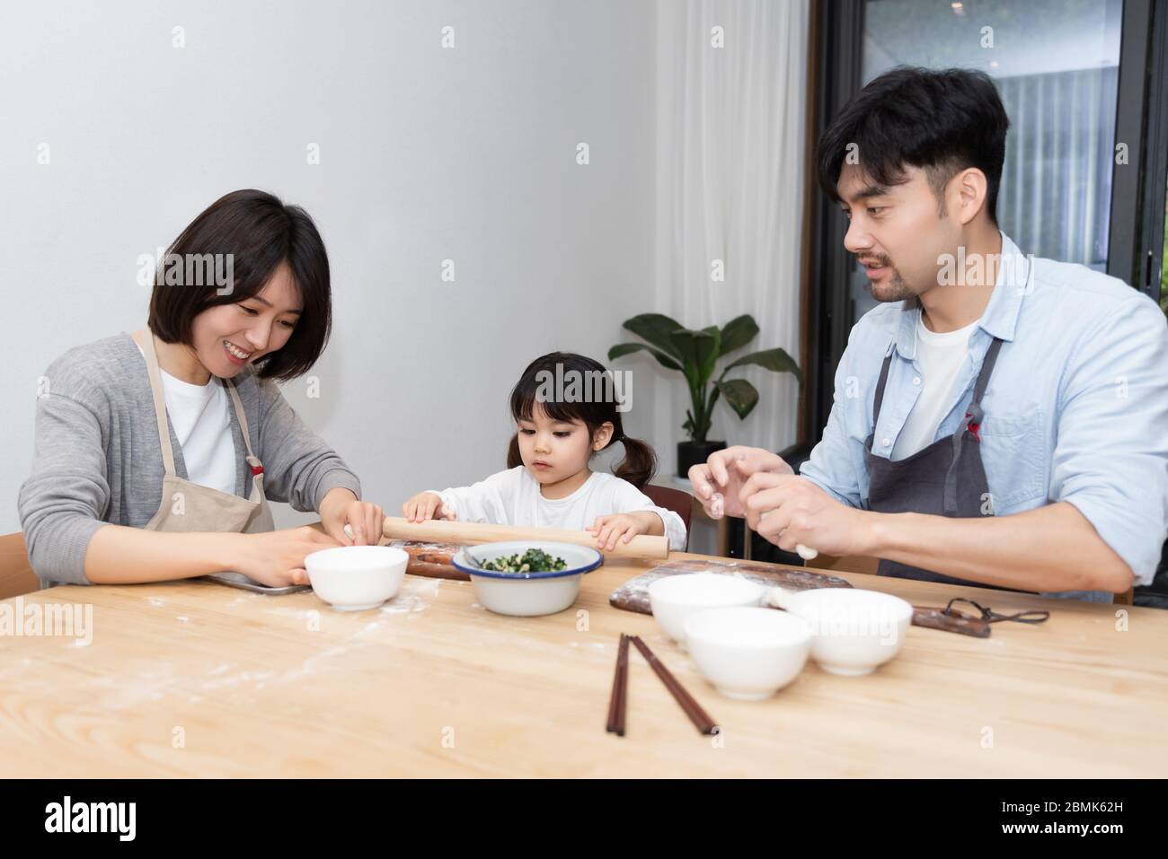 Young Asian mom and dad making dumplings with daughter Stock Photo - Alamy