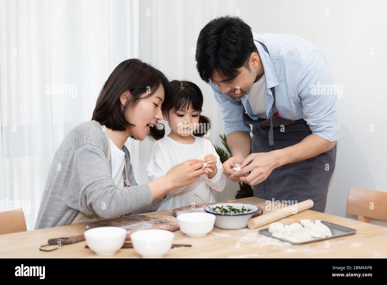 Young Asian mom and dad making dumplings with daughter Stock Photo - Alamy