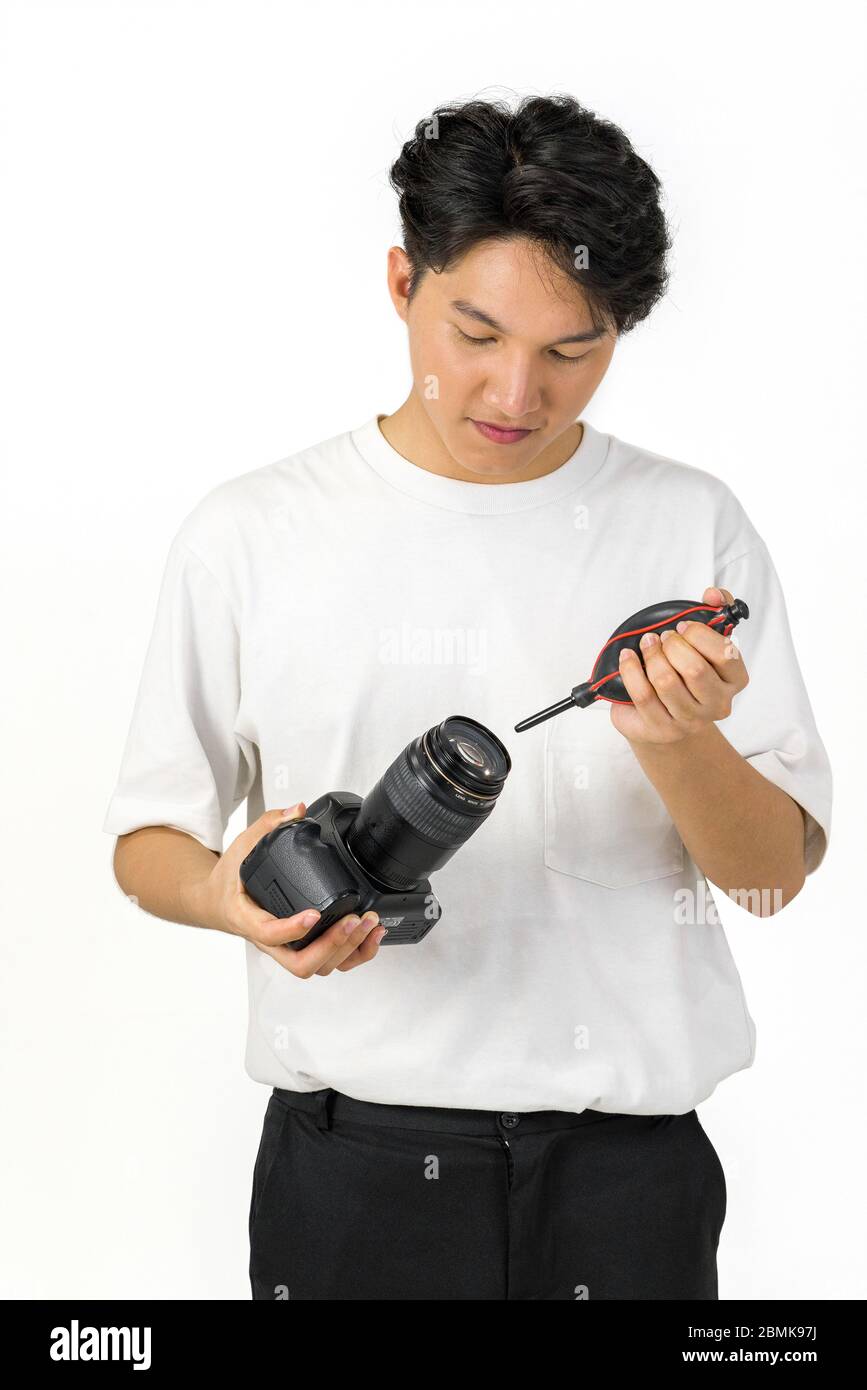 An Asian photographer is cleaning the camera and lens with a air blower ...