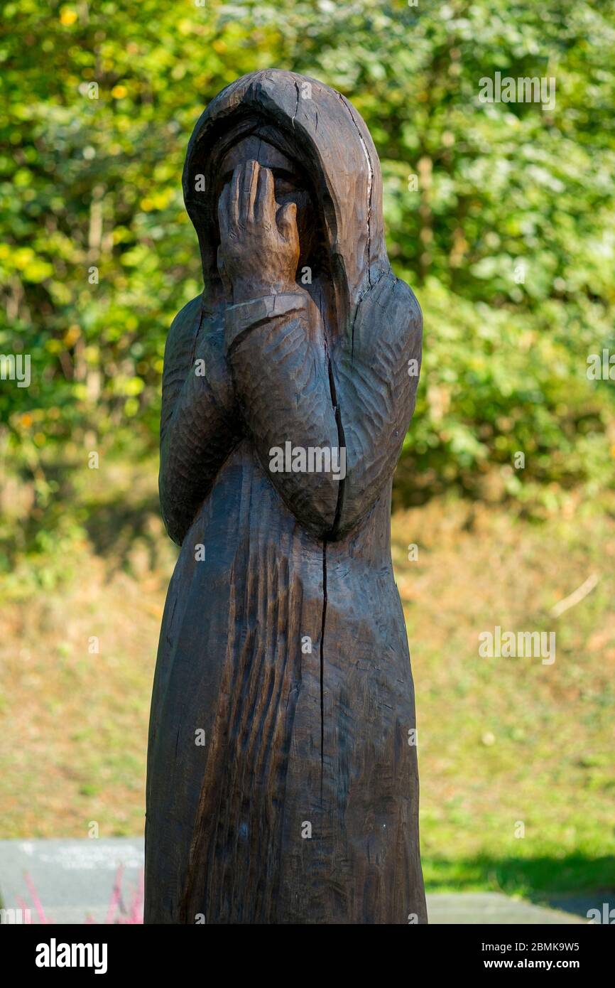 A traditional wood, hand carved folk art memorial sculpture marks a ...