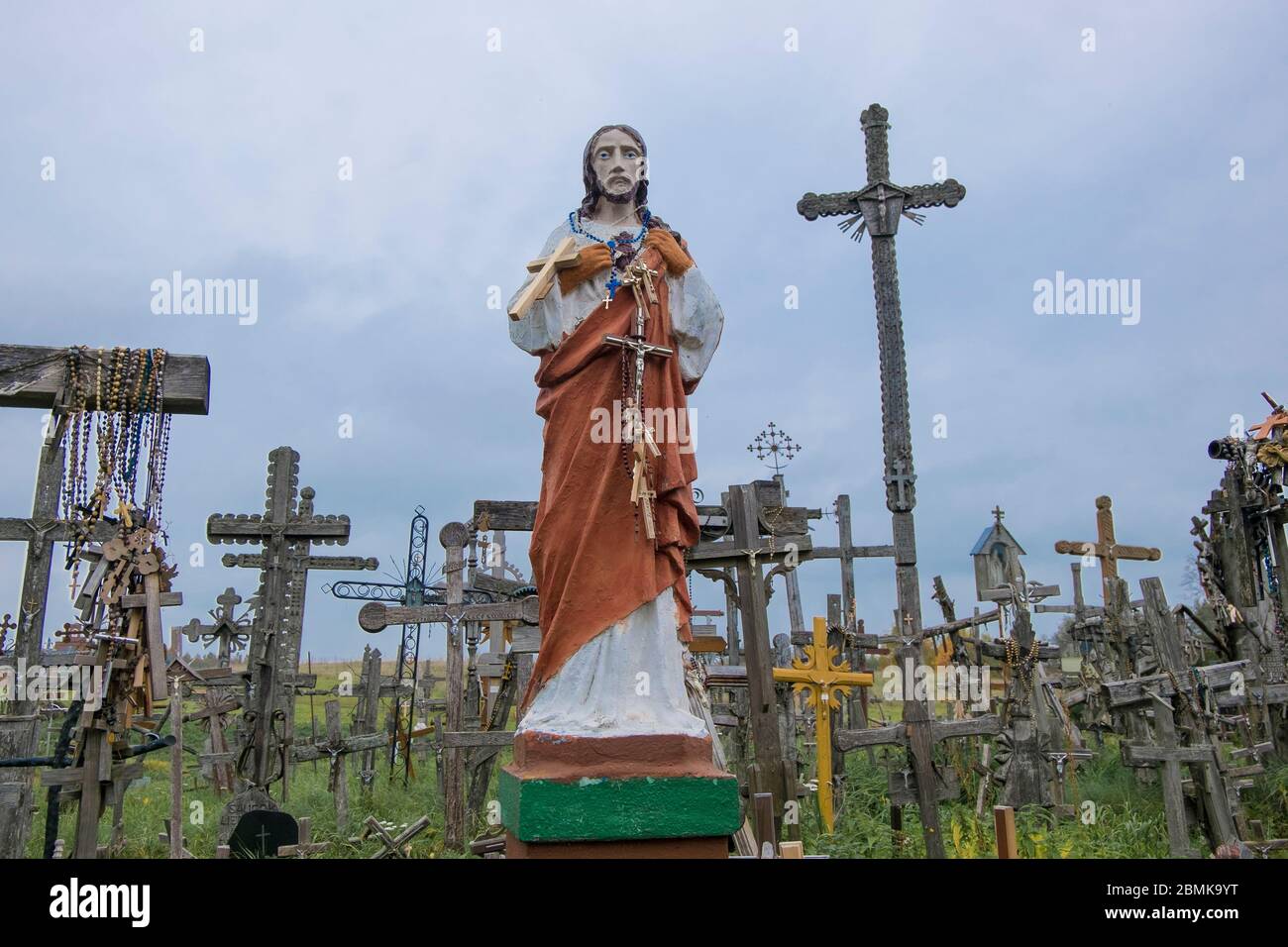 A colorful, concrete statue of Jesus among many crosses. At the Hill of ...