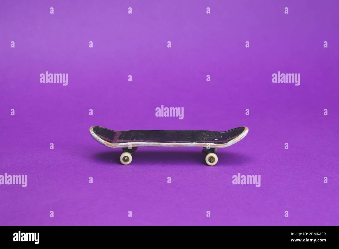 Small skateboard on purple background. tiny skate for fingers ...