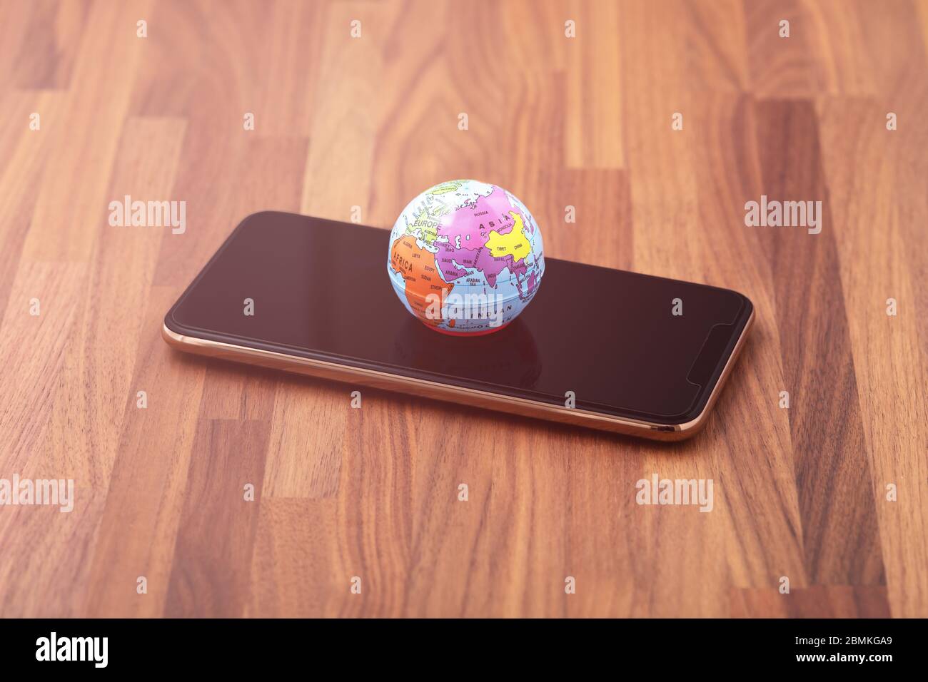 Smart digital world concept. Smartphone with world map on wooden office ...
