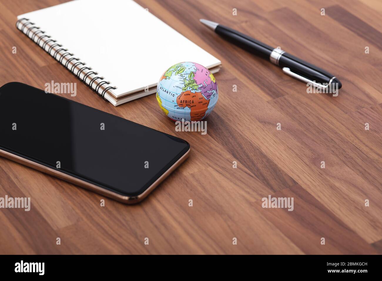 Smart phone with world map and notebook on wooden office desk Stock ...