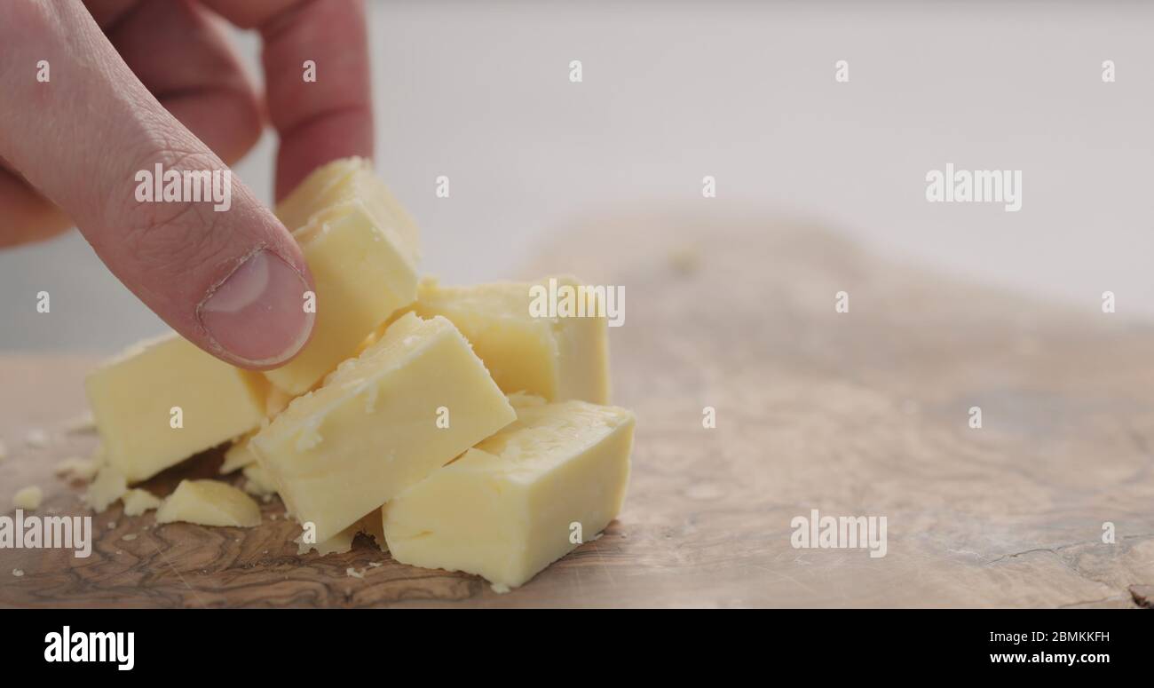 man hand takes cheddar cheese cube from olive wood board closeup Stock ...