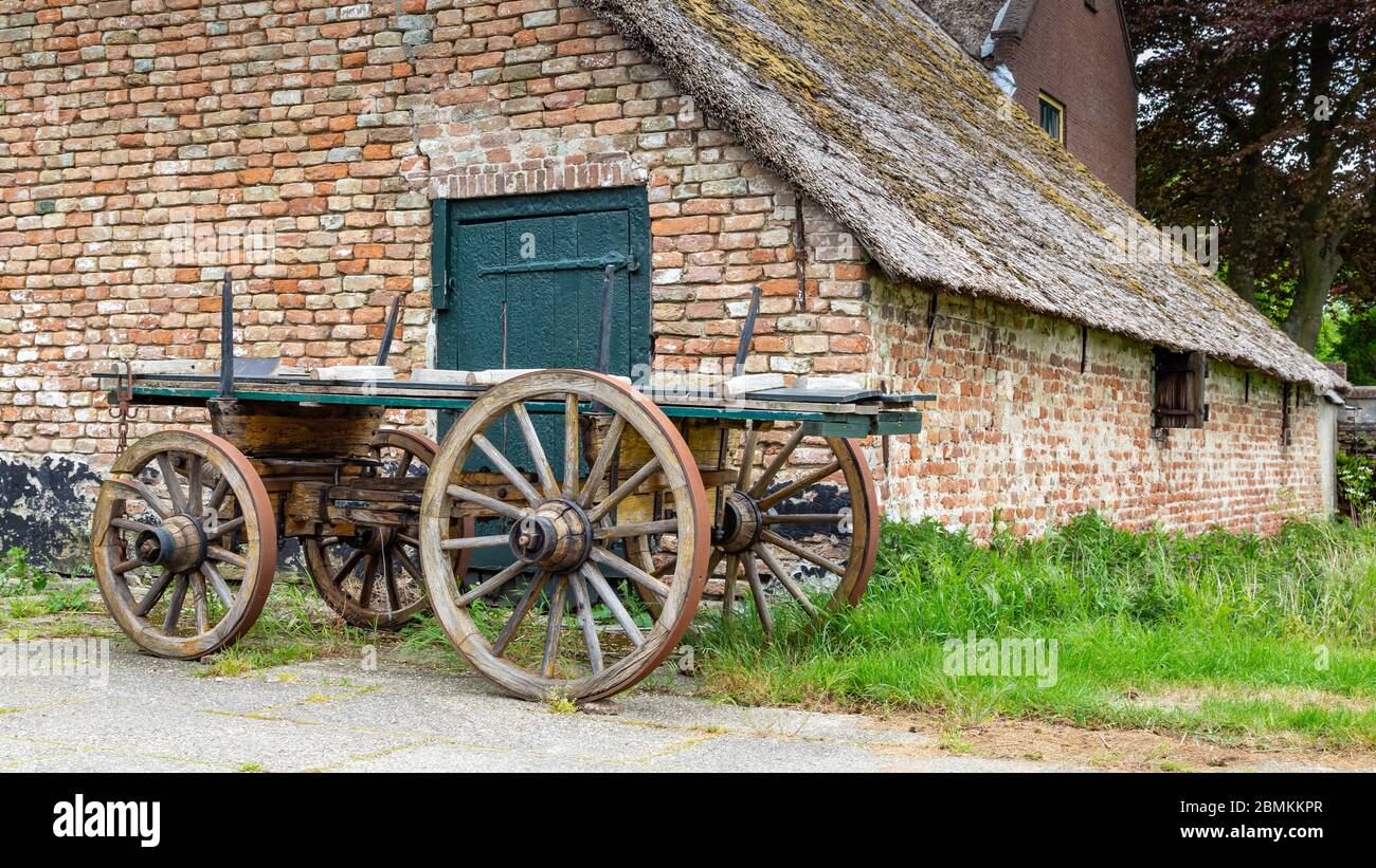 Traditional Dutch farm with thatched roof and an ancientwooden wagon ...