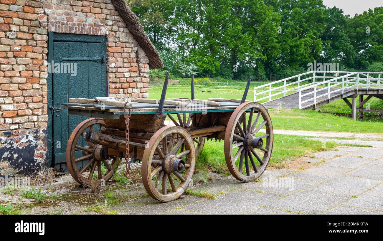Traditional Dutch farm with thatched roof and an ancient wooden wagon ...