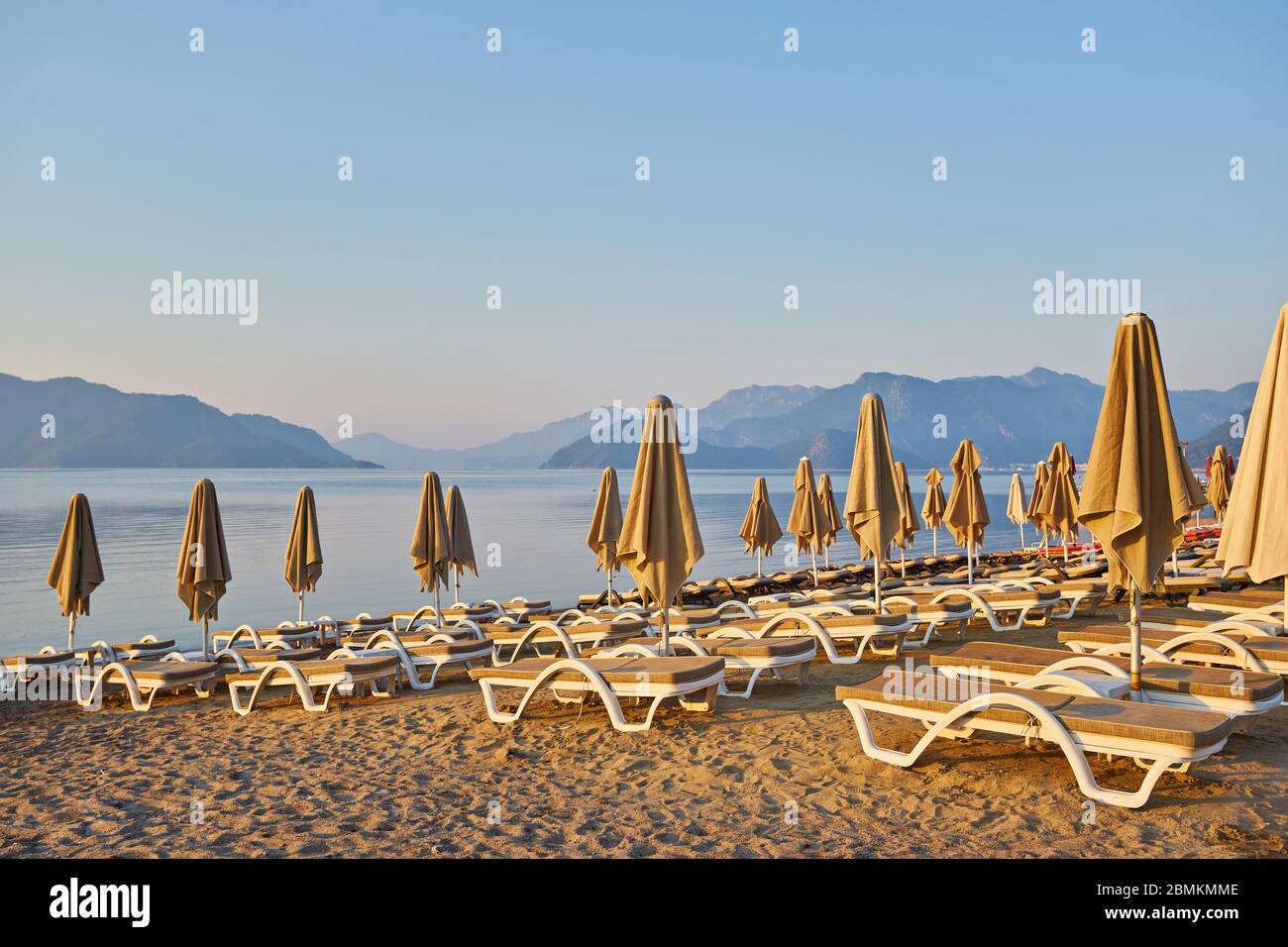 Deserted beach in the morning sun. The beach at dawn. Empty sunbeds ...