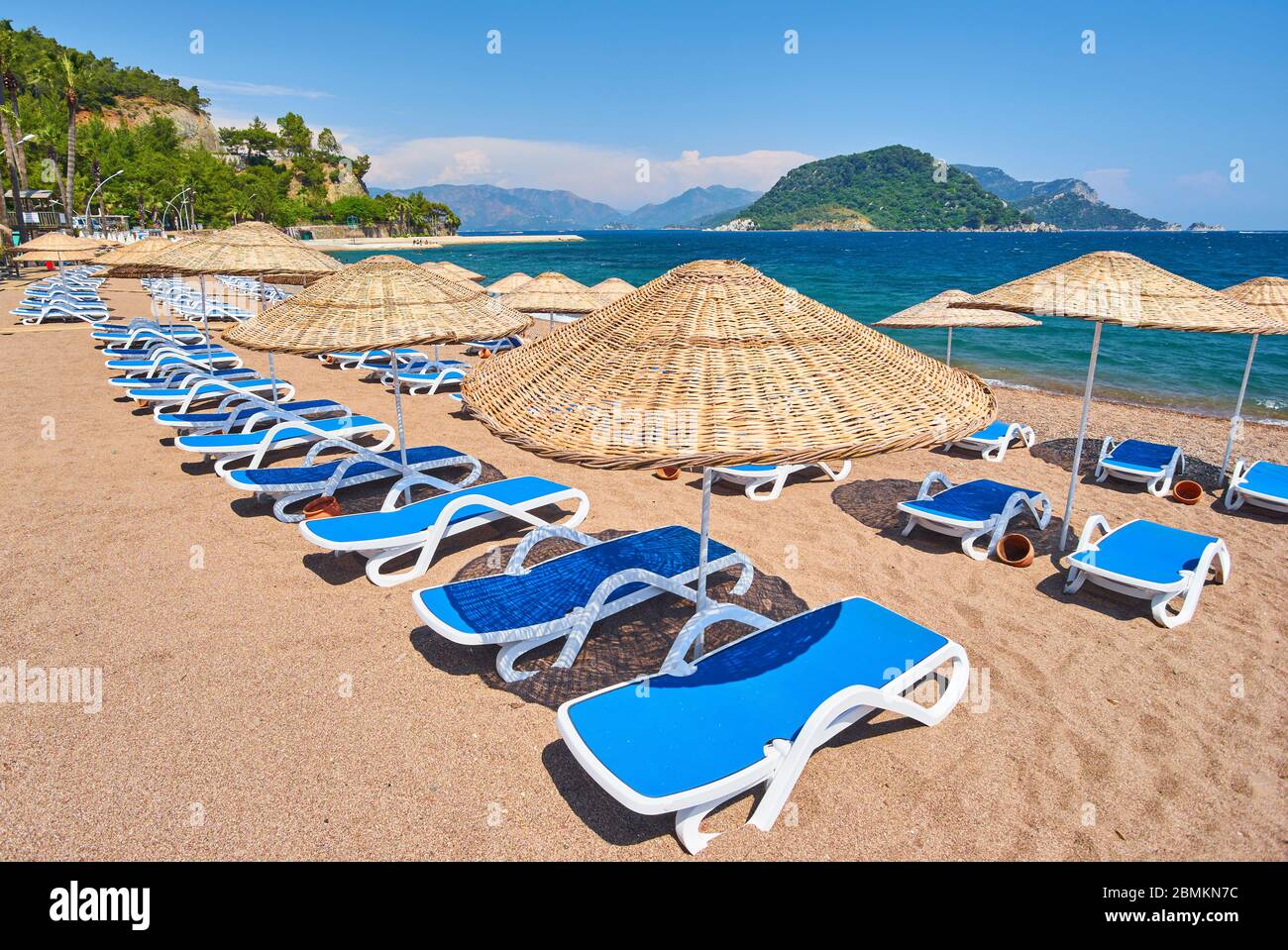 sandy beach without people and with sun loungers, umbrellas, palm trees ...