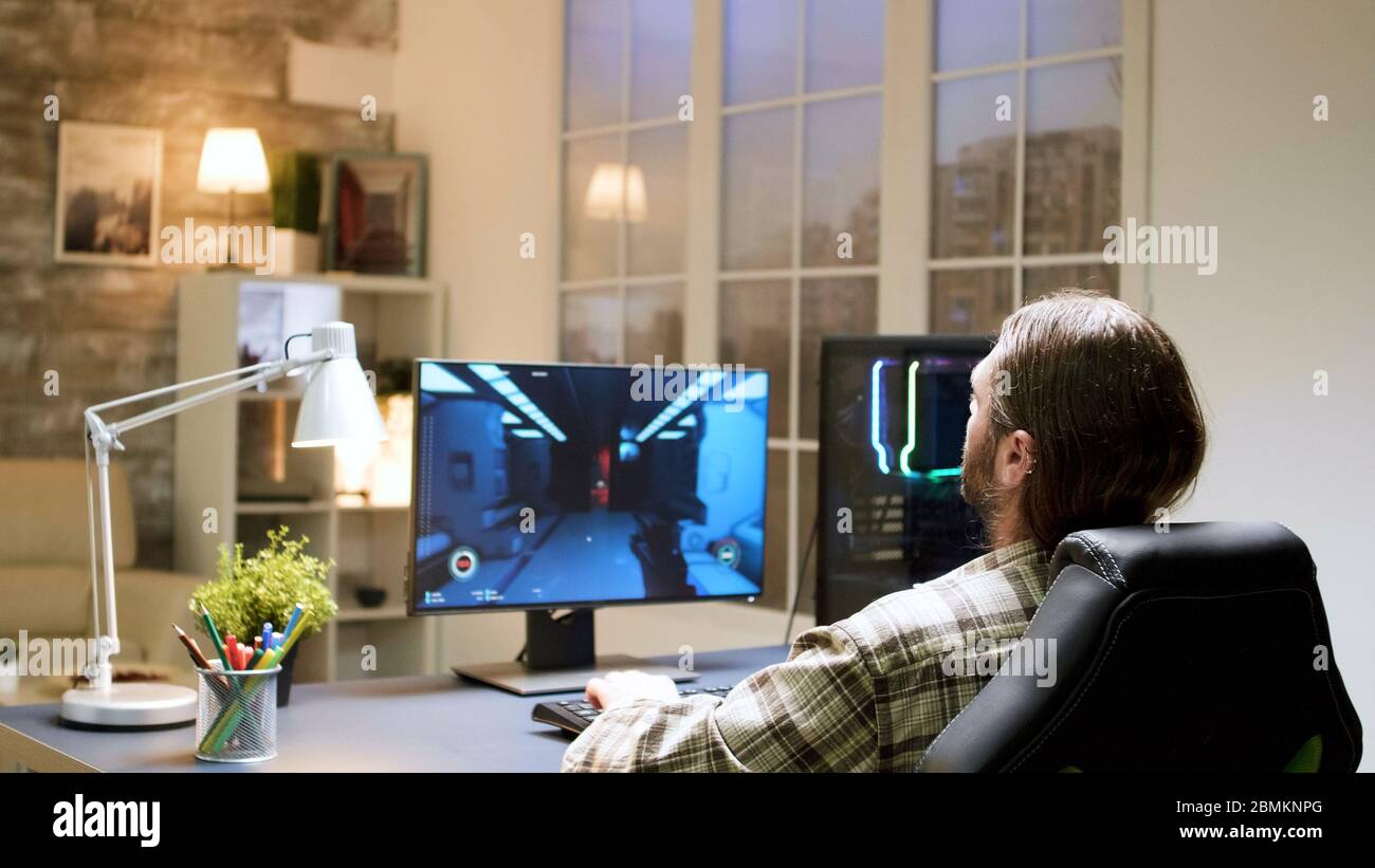Excited young gamer with long hair sitting on gaming chair. Man using ...