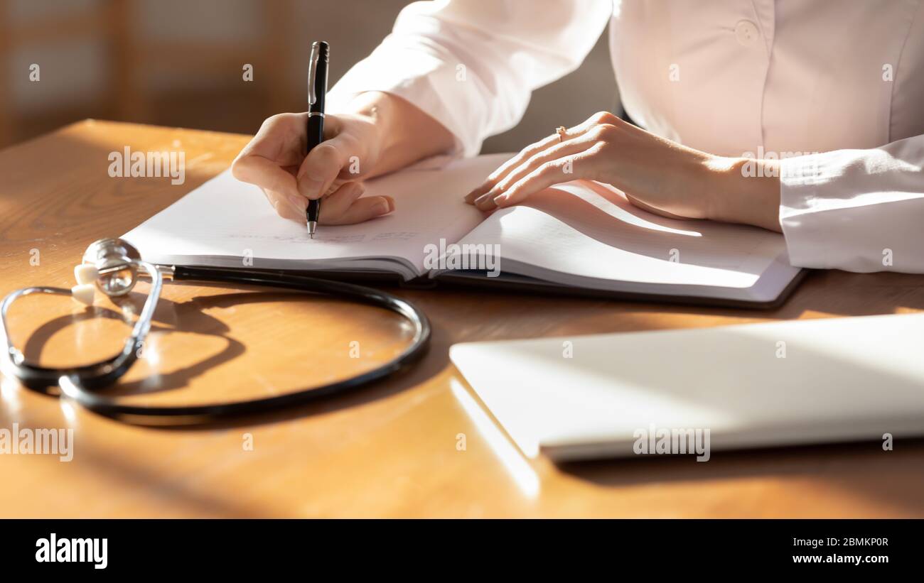 Female doctor write in journal filling medical history Stock Photo - Alamy