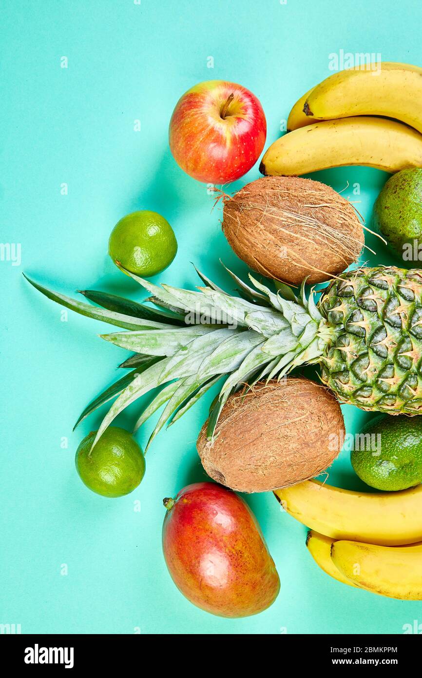 Flat lay of exotic fruits on blue background - mango, pineapple, banana ...