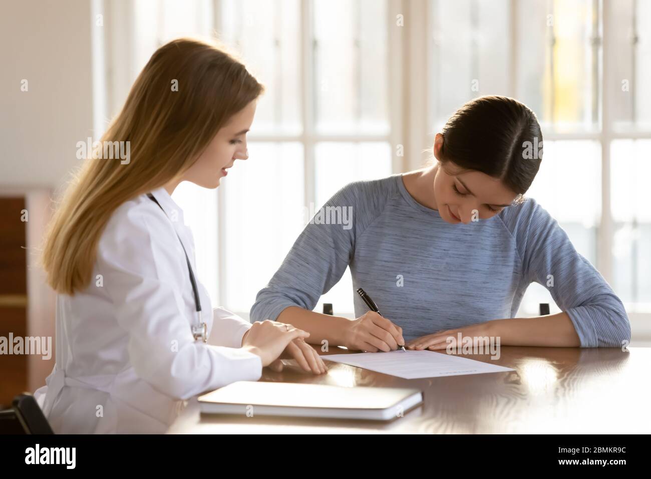 Female patient sign paper contract at meeting with doctor Stock Photo ...