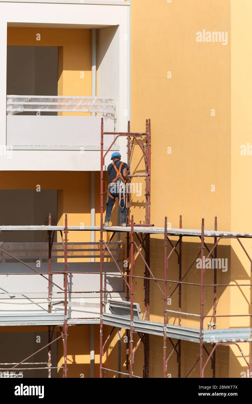Worker with Blue Hardhat at Work on a Scaffold in a Building Site for ...