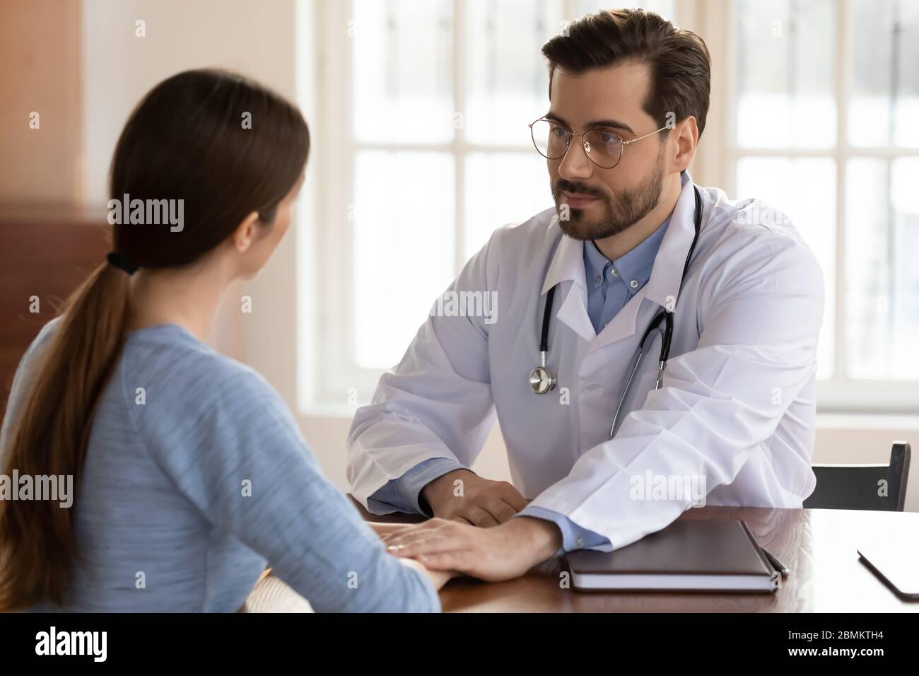 Male doctor comfort upset female patient at consultation Stock Photo ...