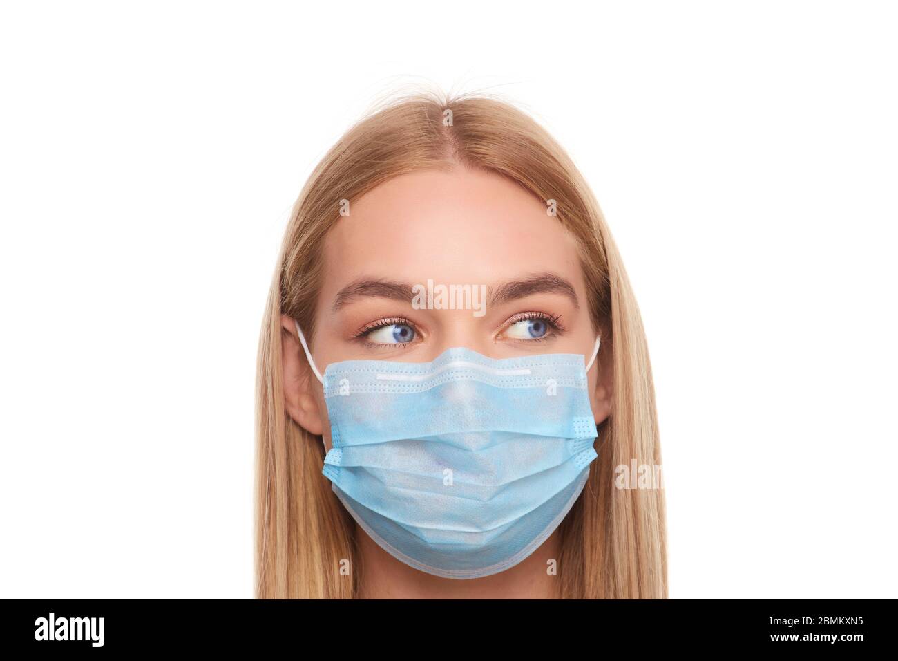 female face in a medical mask with eyes looks away on a white ...
