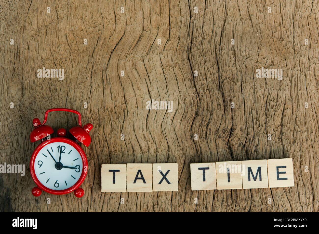 Red alarm clock and Tax time with wooden alphabet blocks, on plank ...