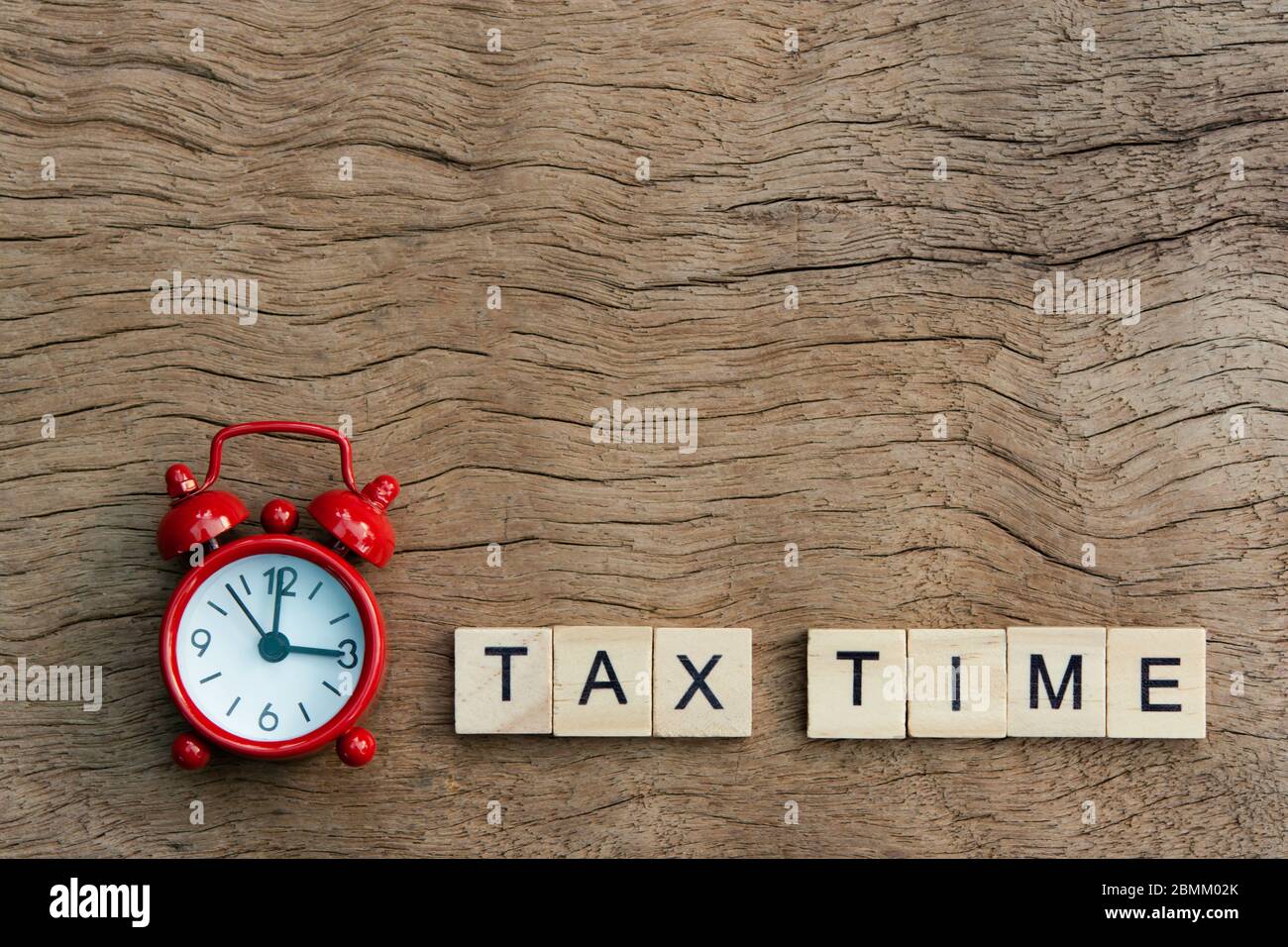 Red alarm clock and Tax time with wooden alphabet blocks, on plank ...