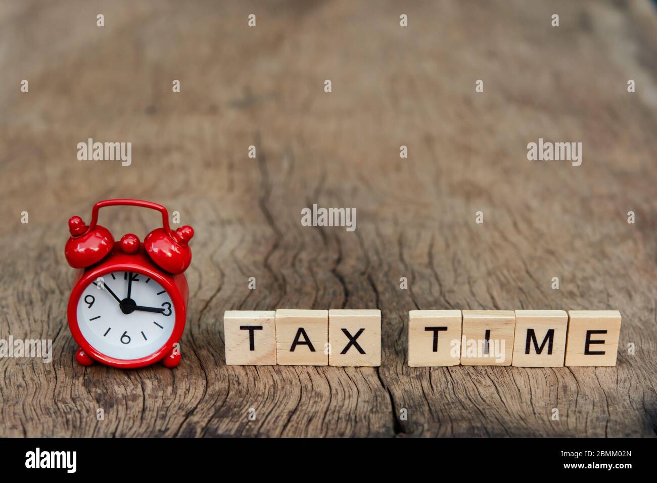 Red alarm clock and Tax time with wooden alphabet blocks, on plank ...