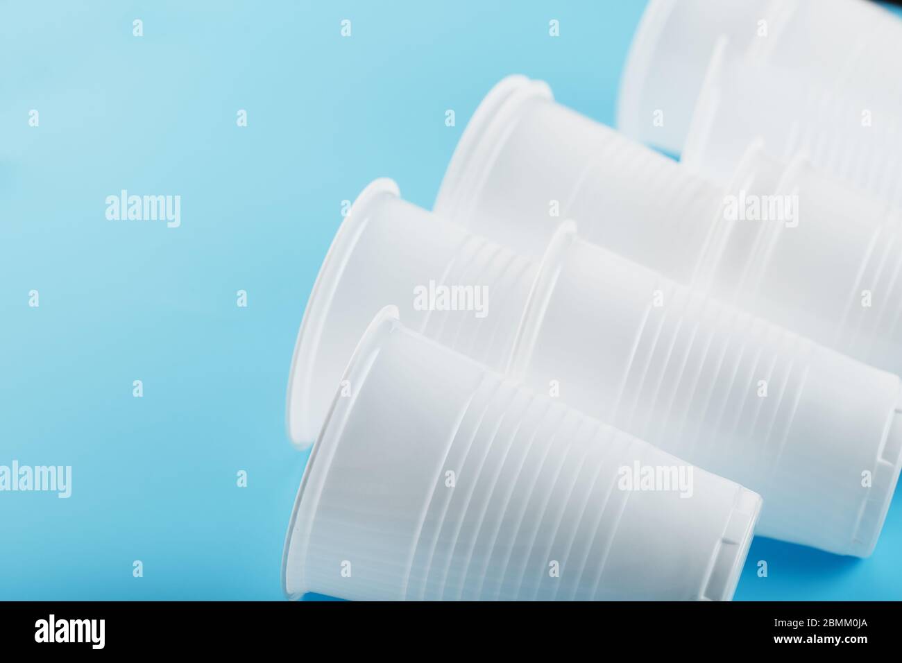 Plastic cups of disposable tableware on a blue background. Free space ...