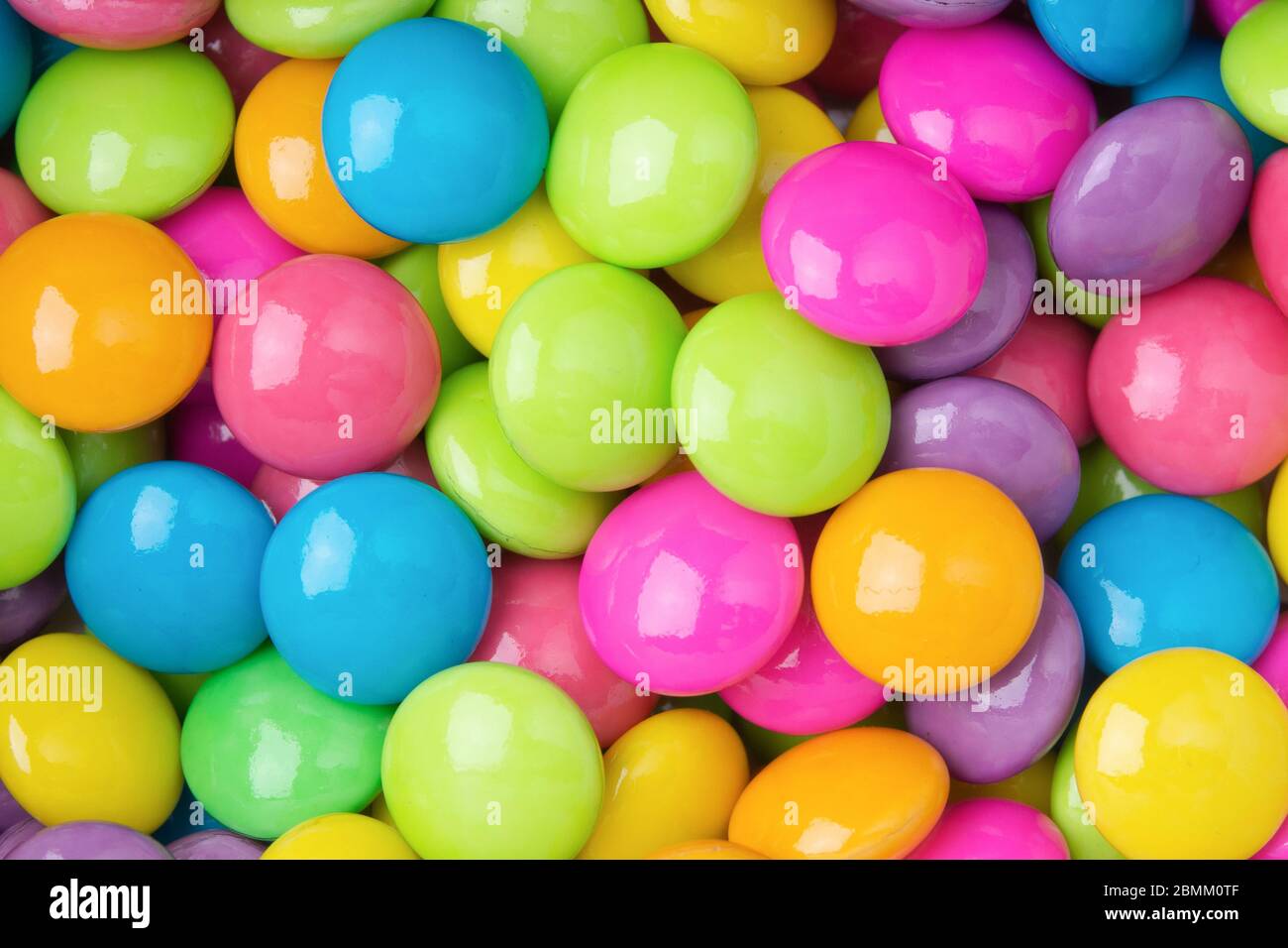 Pile of colorful sweet candy chocolates coated on white paper ...