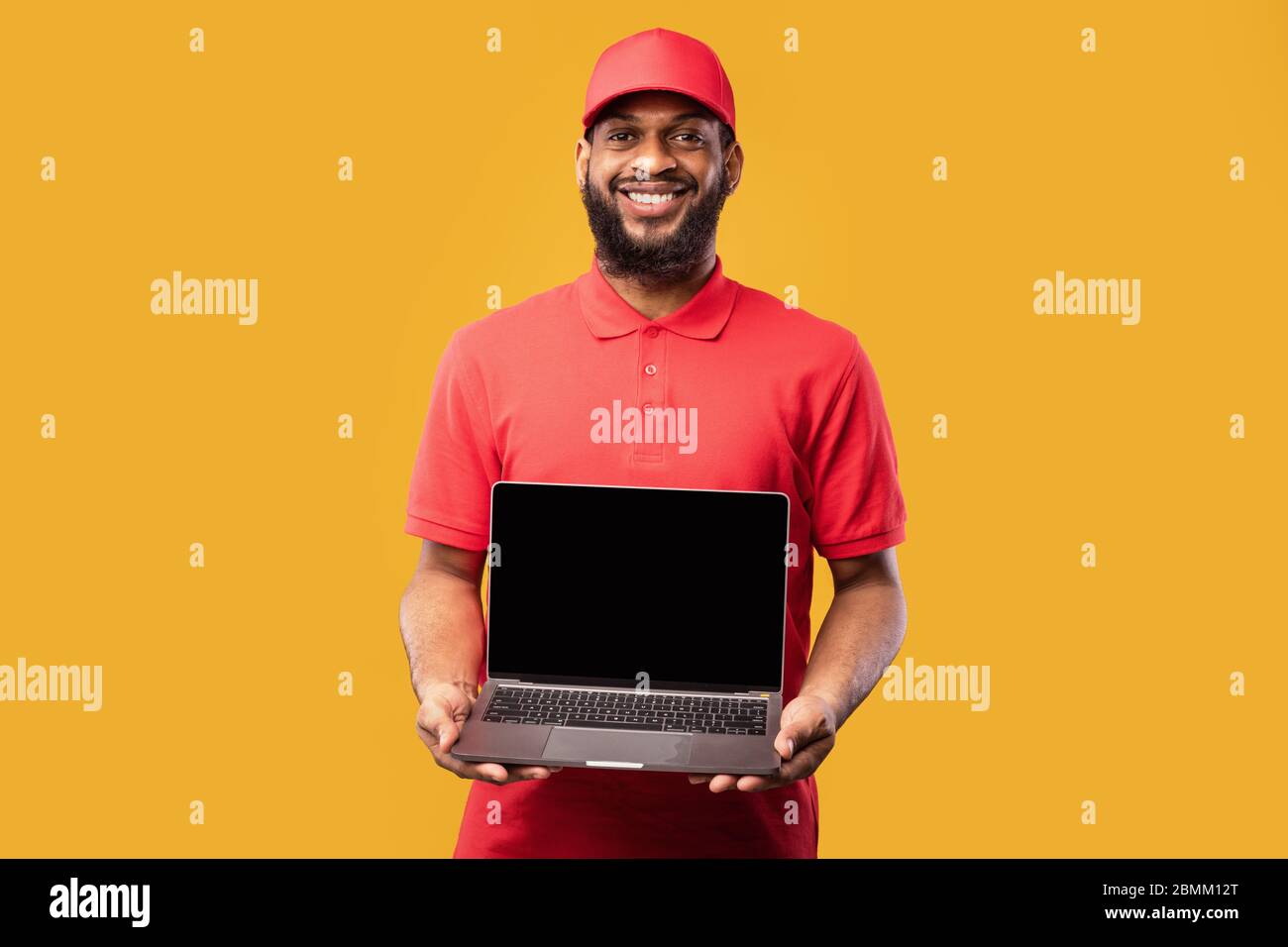 Delivery Man Holding Laptop With Empty Screen Standing In Studio Stock ...