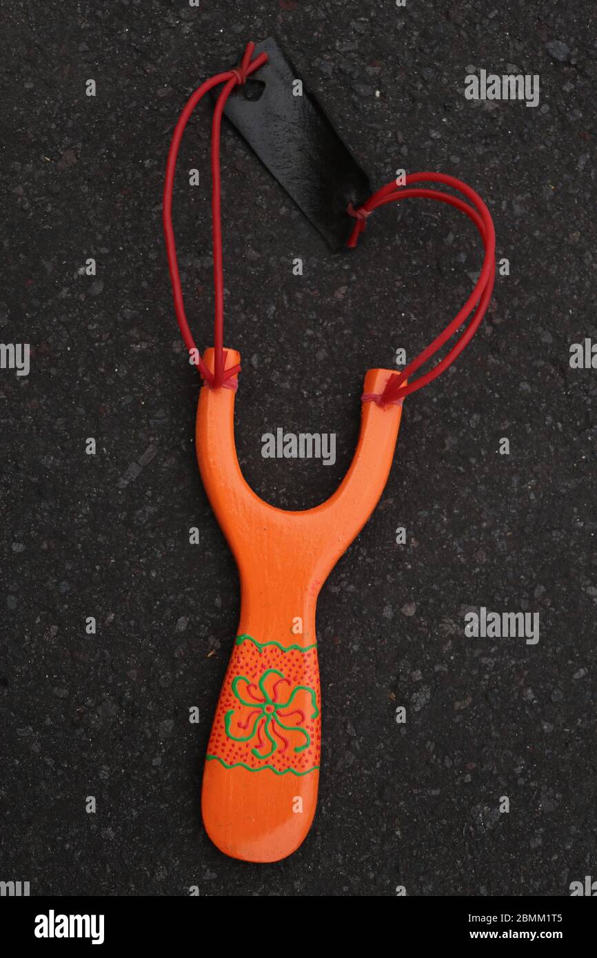 Handmade orange slingshot catapult. Y-shaped wooden stick with elastic ...